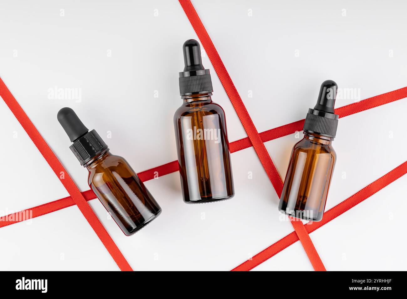 Brown glass dropper bottles elegantly arranged on a white surface with ...