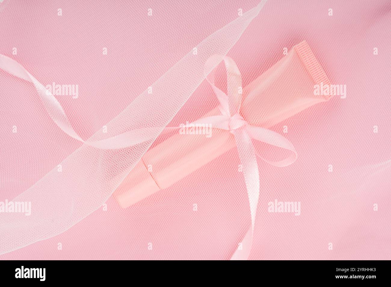 A delicate cosmetic package wrapped in pink tulle and adorned with a ...