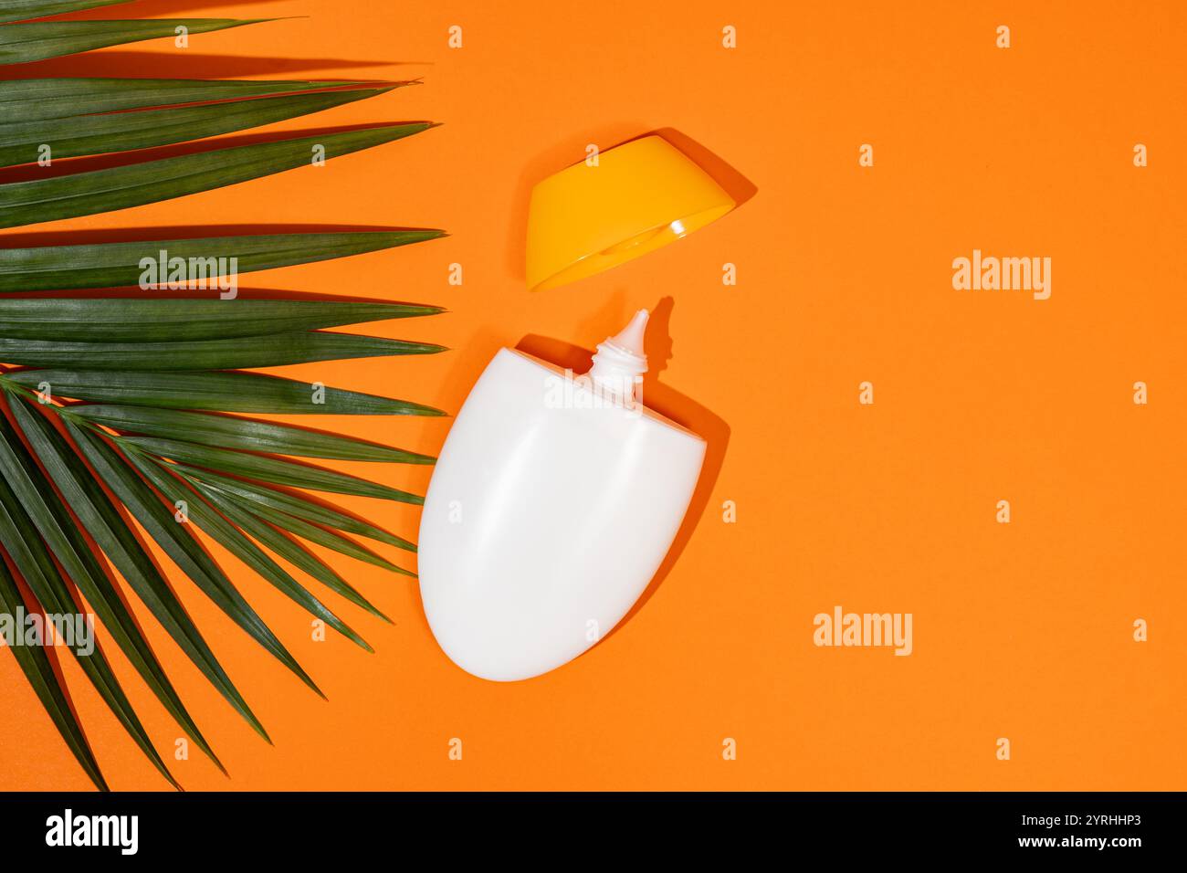 White sun protective cream container with yellow cap on vibrant orange ...