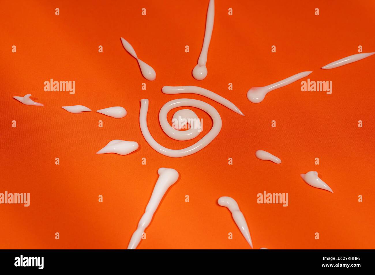 White sunscreen cream forms a sun shape on a bright orange background ...