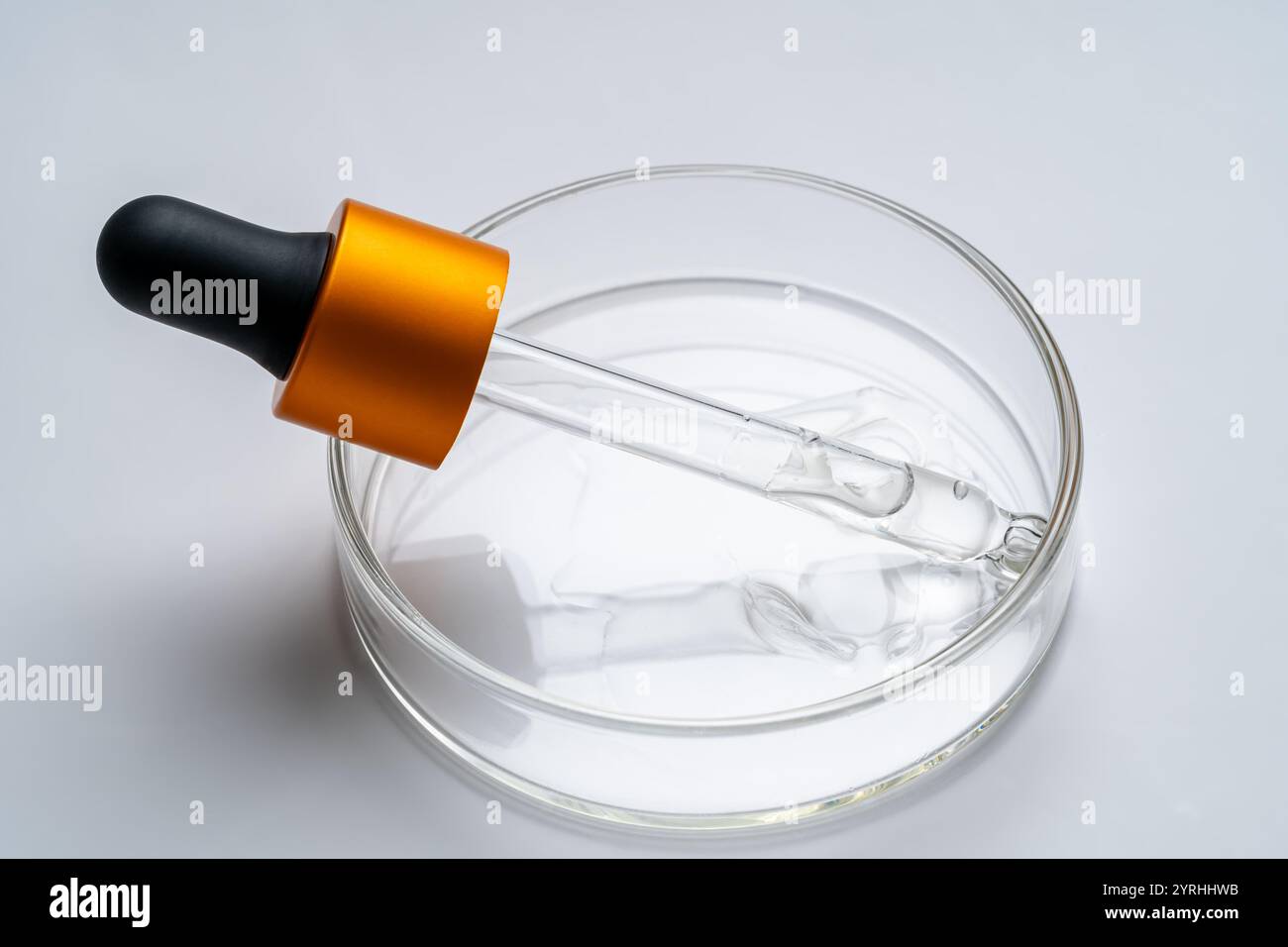 A close-up image of a transparent dropper pipette with an orange cap ...