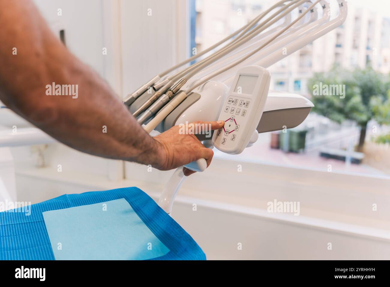 A dentist adjusts the control panel of a dental chair, with various ...
