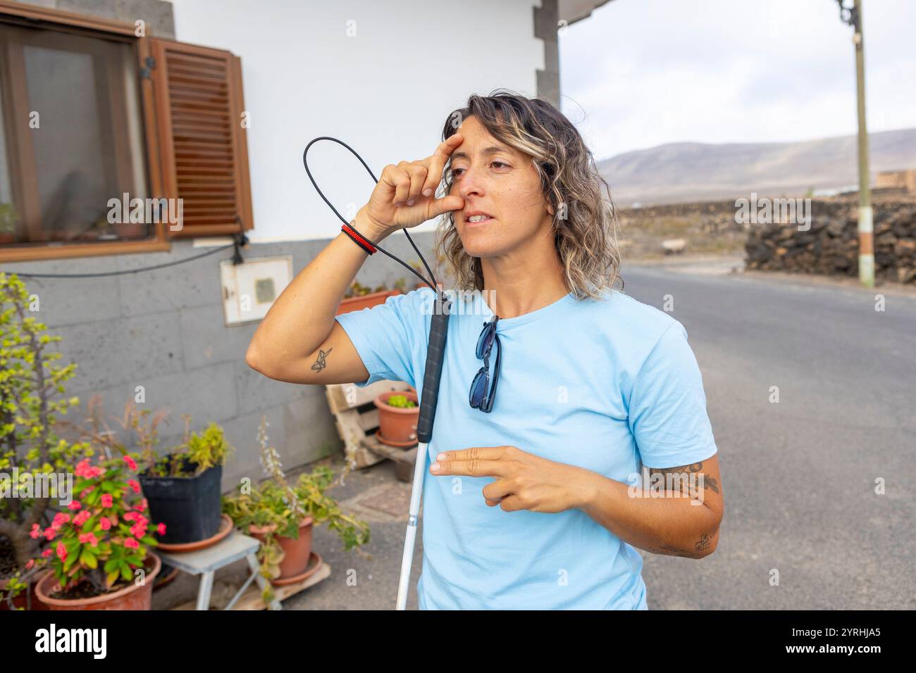 A woman uses a cane and sign language on a street, showcasing ...