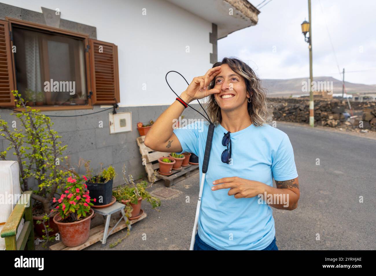 A joyful woman with deaf-blindness using a cane outside, embodying ...