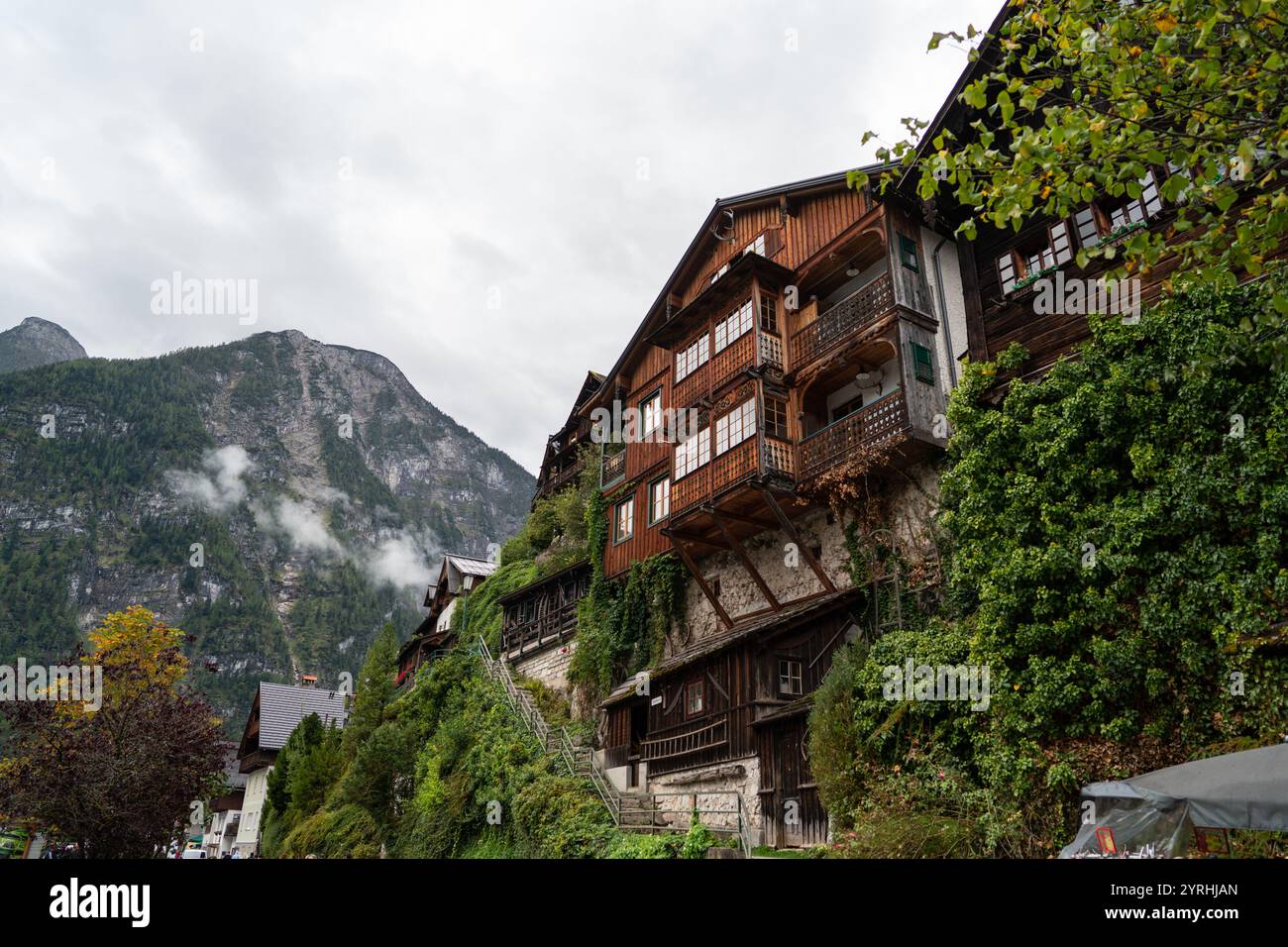 Traditional wooden houses cling to a lush hillside in Hallstatt ...
