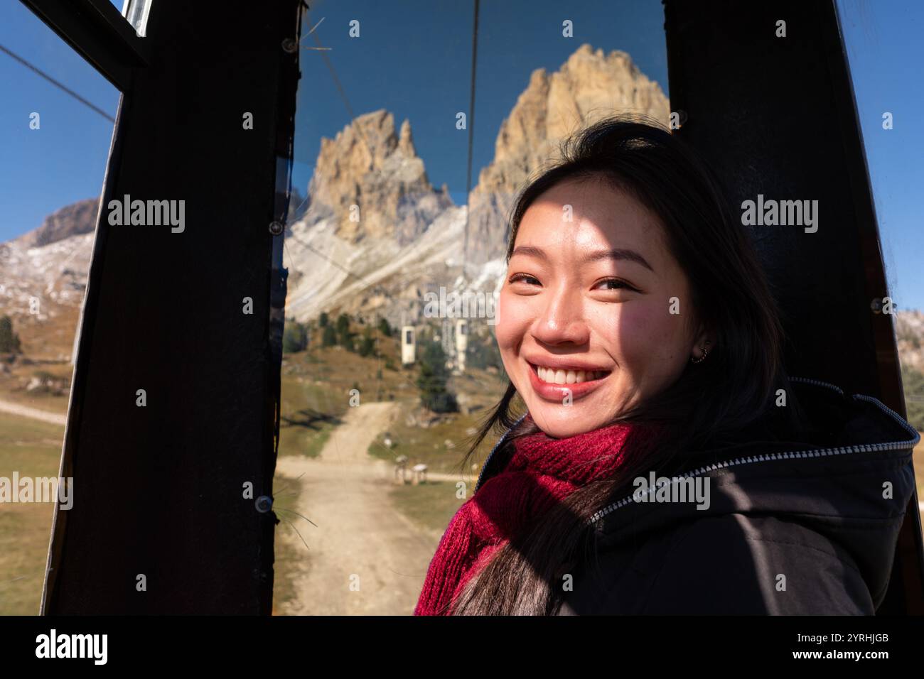 Smiling asian woman enjoys a cable car ride in Forcella del Sassolungo ...