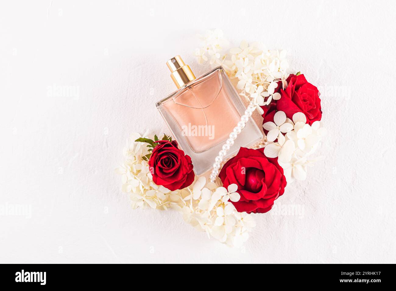A sophisticated perfume bottle is elegantly set amidst vibrant red ...
