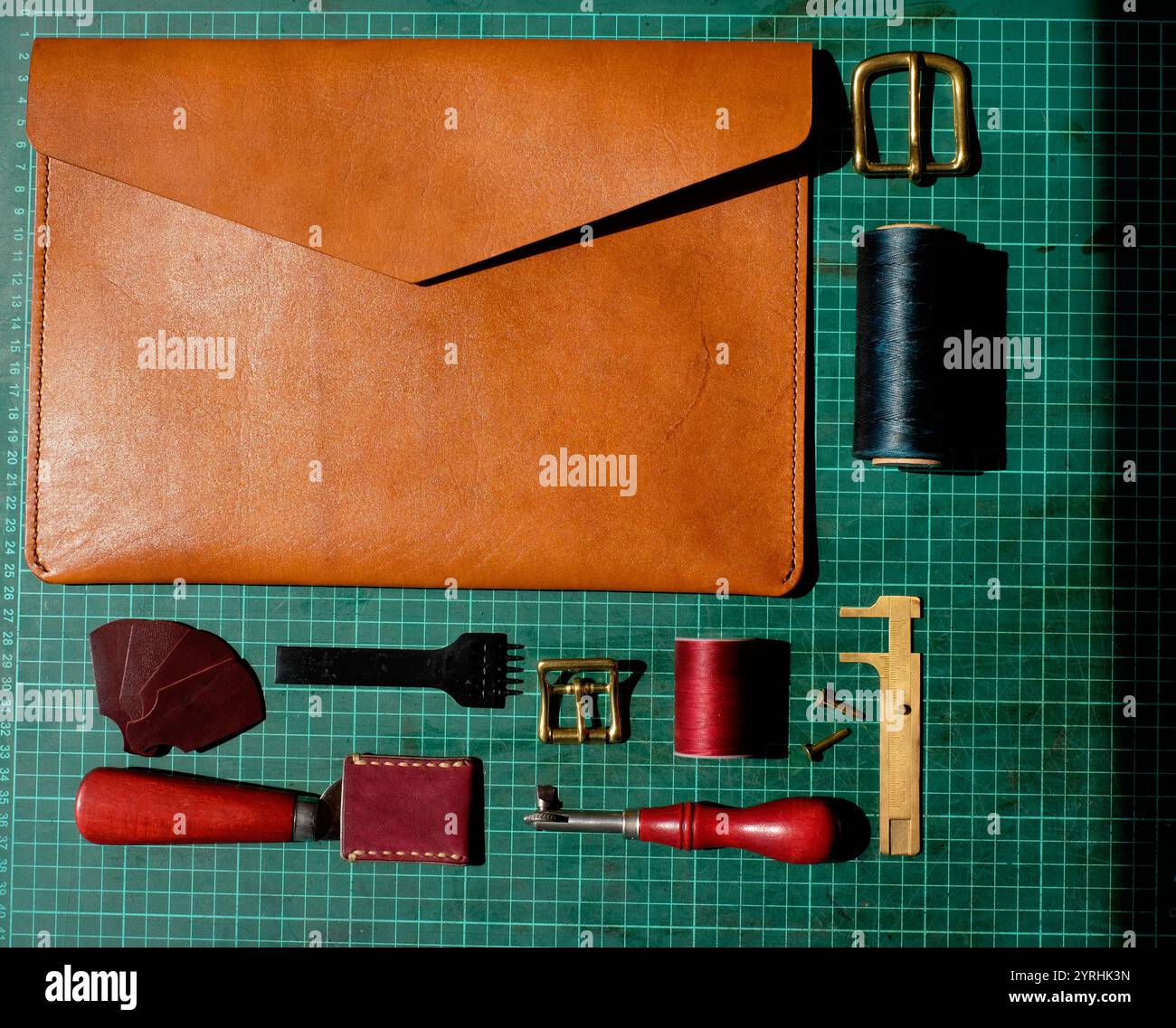 A selection of leather crafting tools and materials on a gridded ...