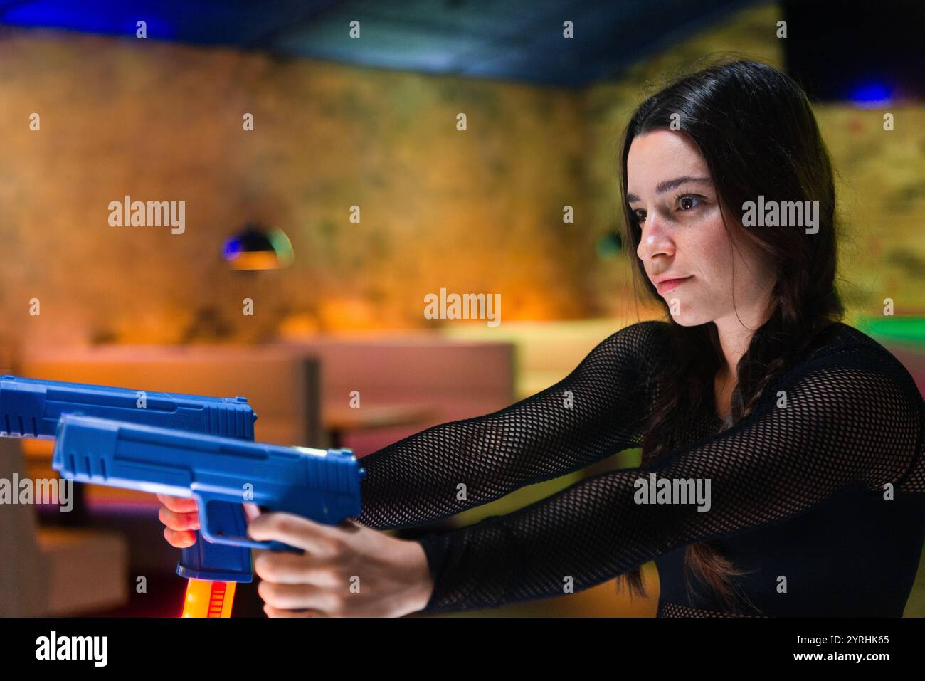 Young woman intensely focused on playing an arcade shooting game ...