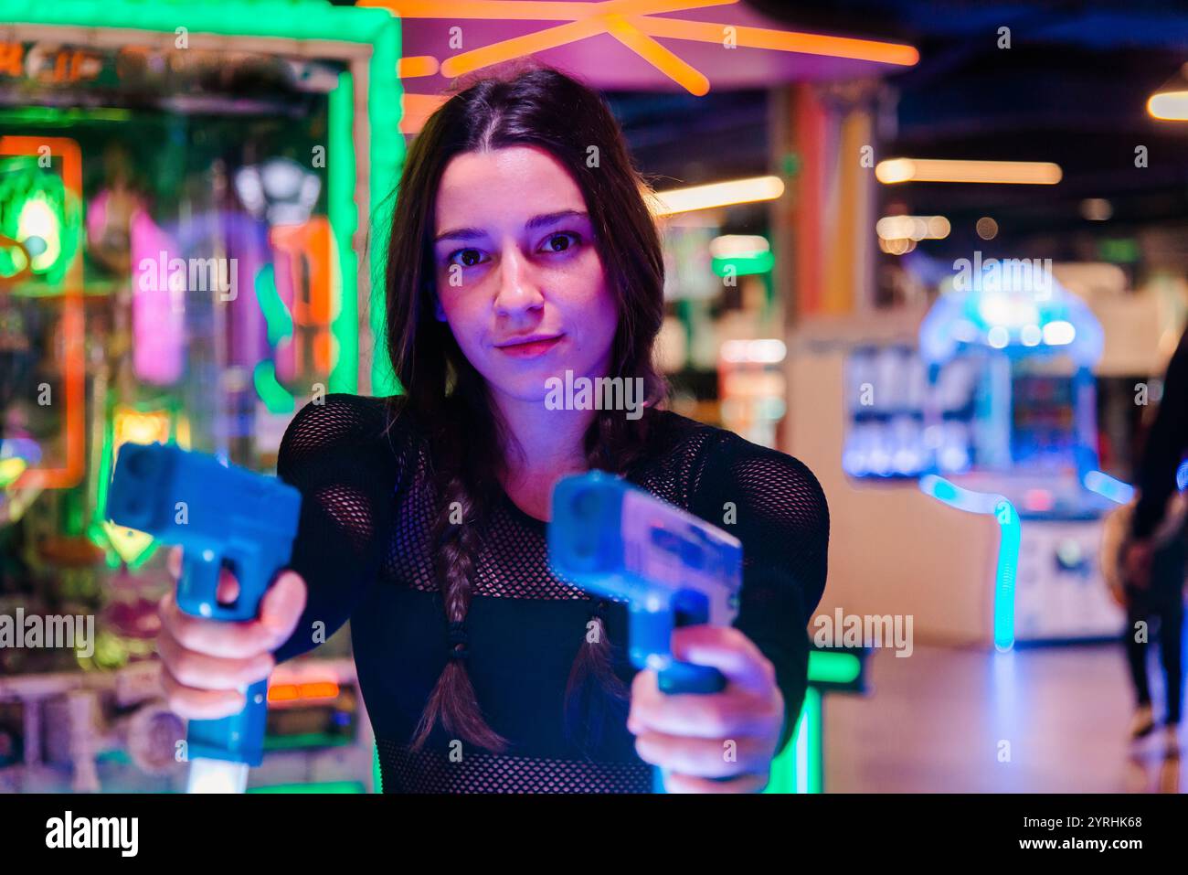 A gamer girl enjoys the arcade, wielding dual light guns in a colorful ...