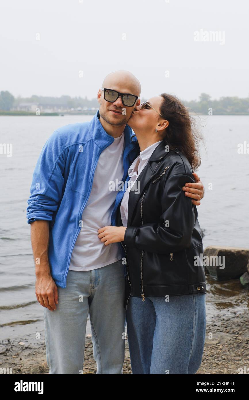 A blind couple enjoys a tender moment by a lake. The blind woman gives ...
