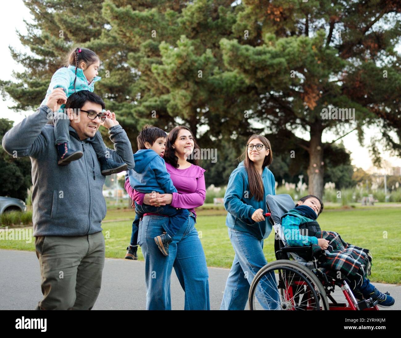 Latin family spends quality time in a park Parents carry their children ...