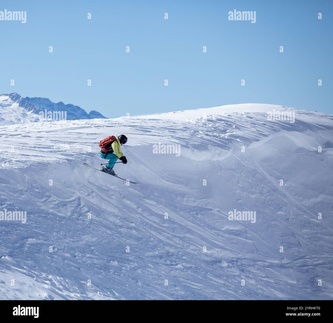A female skier, dressed in bright winter gear, deftly jumping a snowy ...
