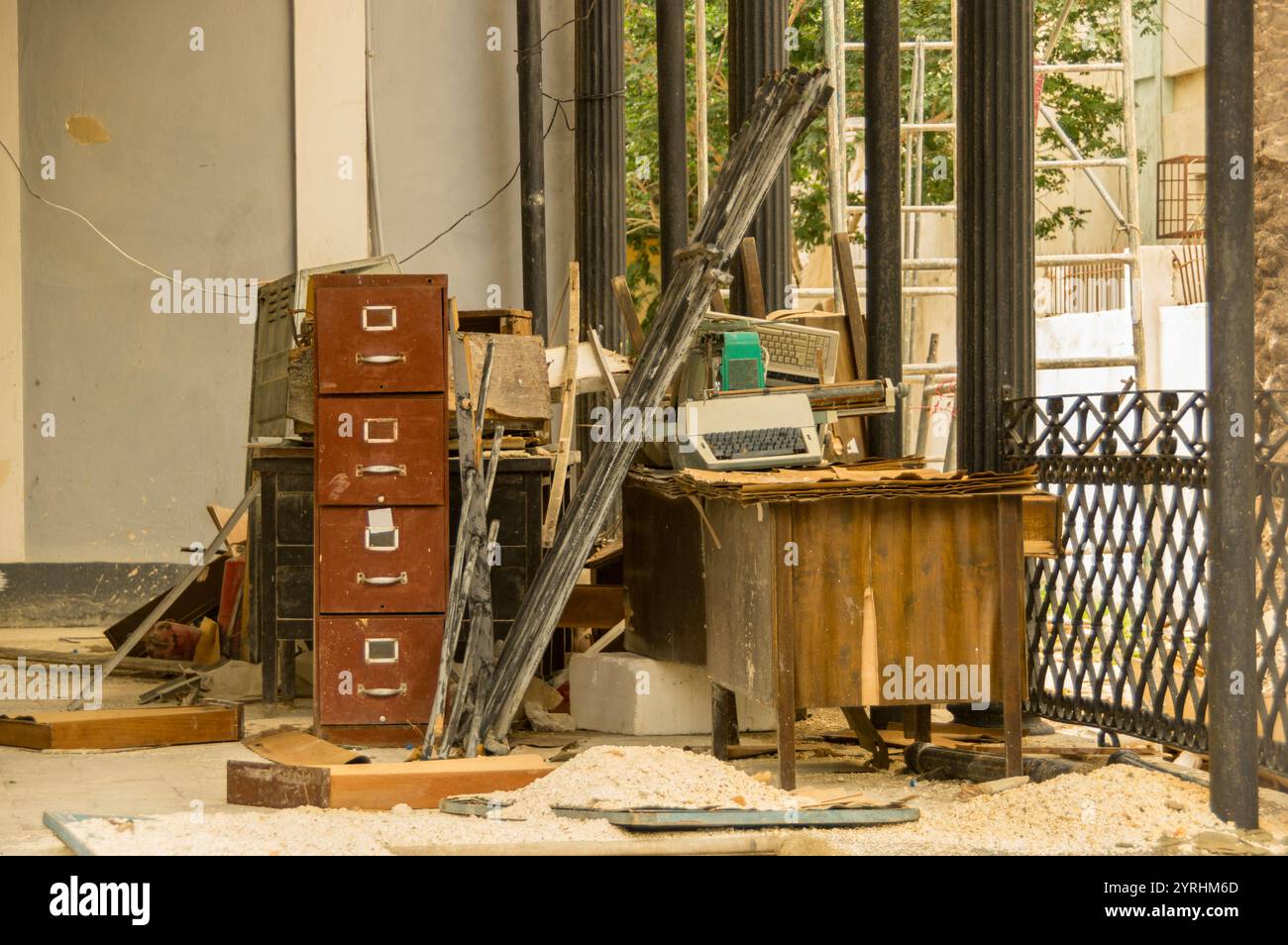 A cluttered, abandoned workspace featuring a rusty file cabinet, a ...