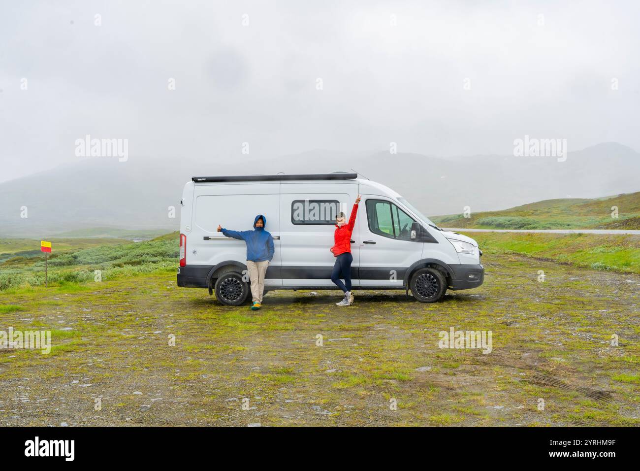A camper van parked in the Swedish countryside with two happy travelers ...