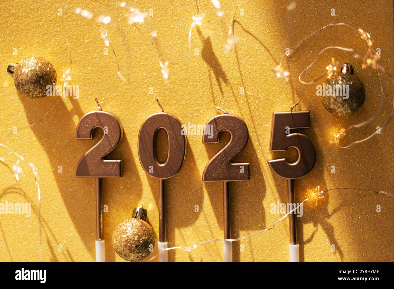 Golden New Year 2025 candles with stars, lights and gold balls lie on a ...
