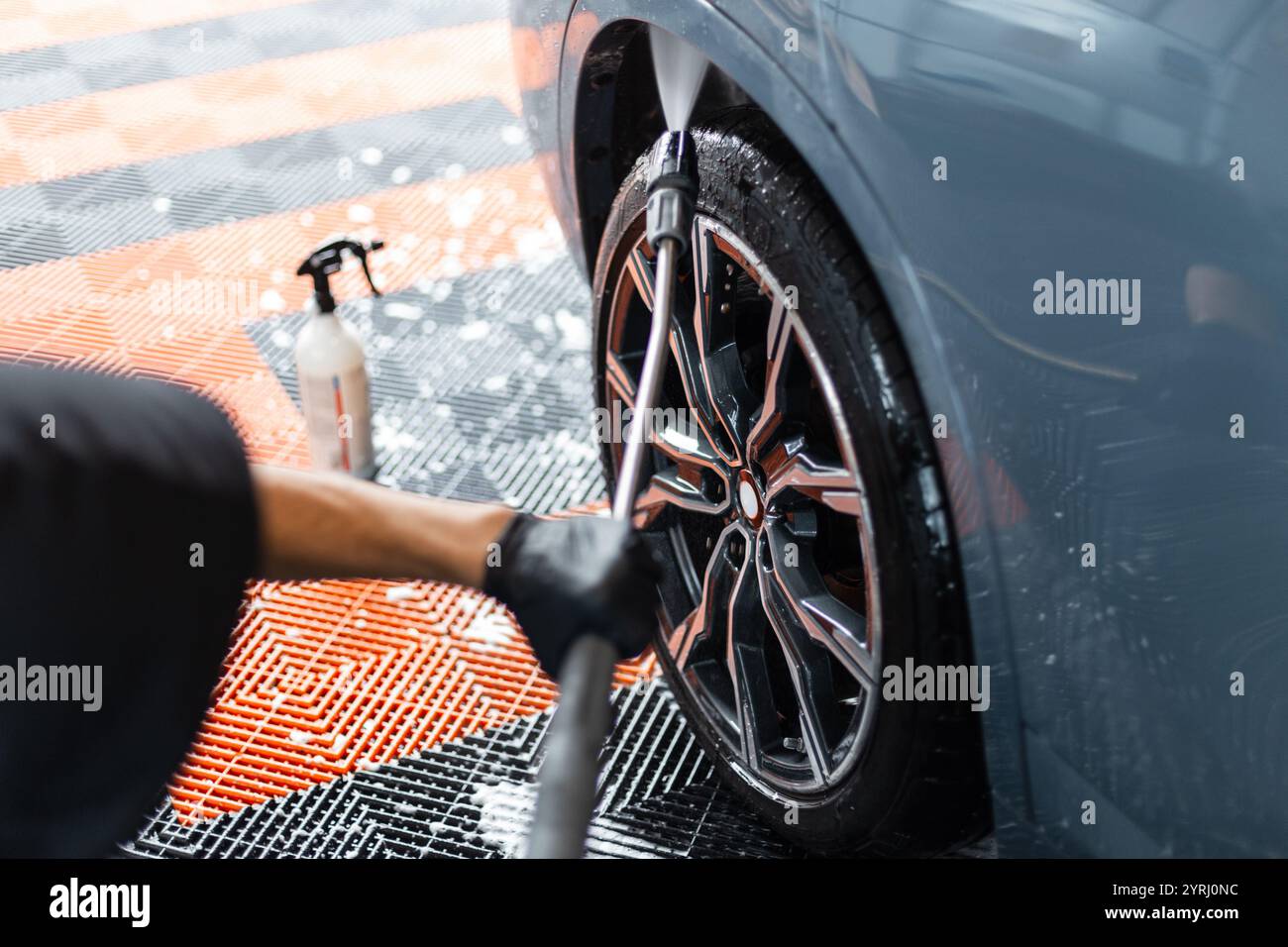 Professional man washing car wheels in garage. Car wash and detailing ...