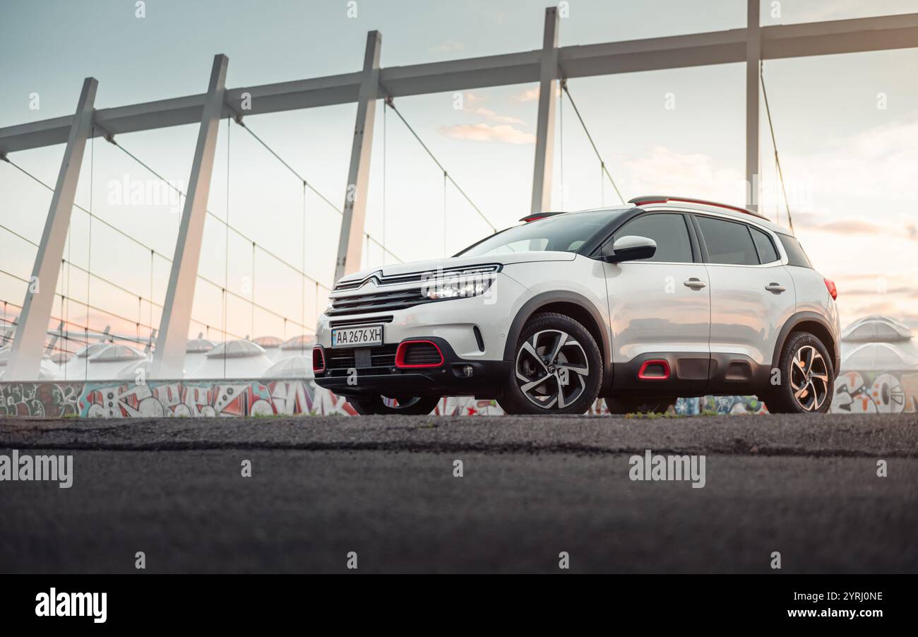 White Citroen C5 Aircross in a big parking lot at sunset. Low-angle ...