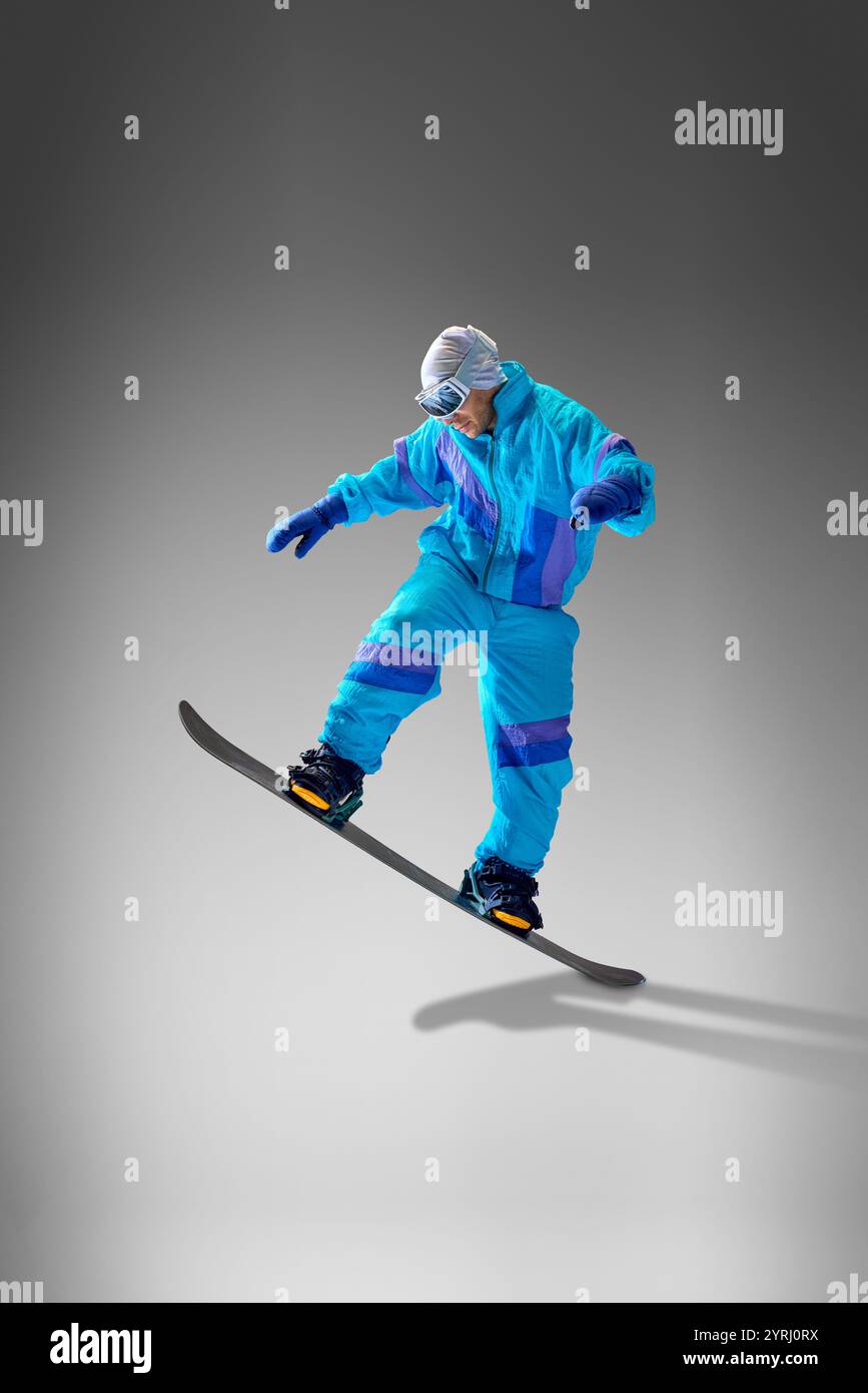 Snowboarder showcasing dynamic moves in bold gear, against grey studio ...