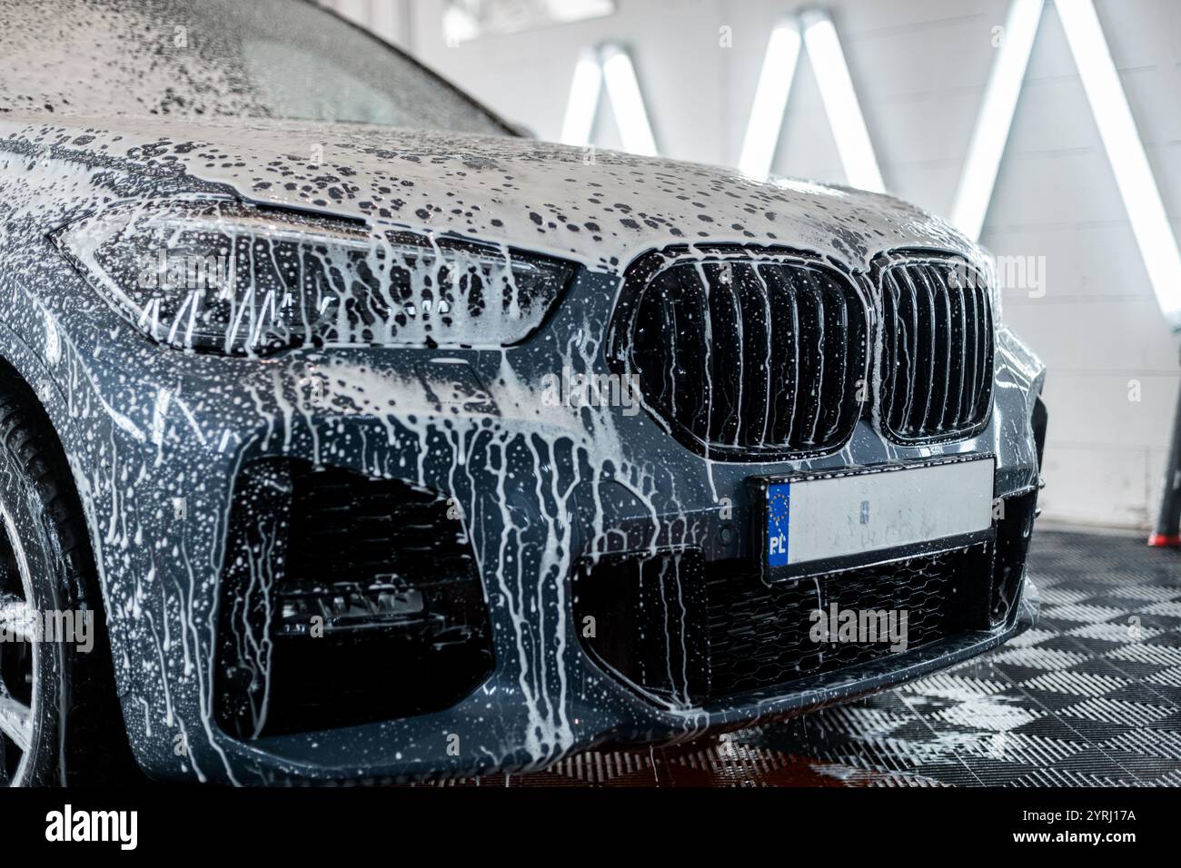 Car is washed at a professional car wash. Man washes a car with foam ...