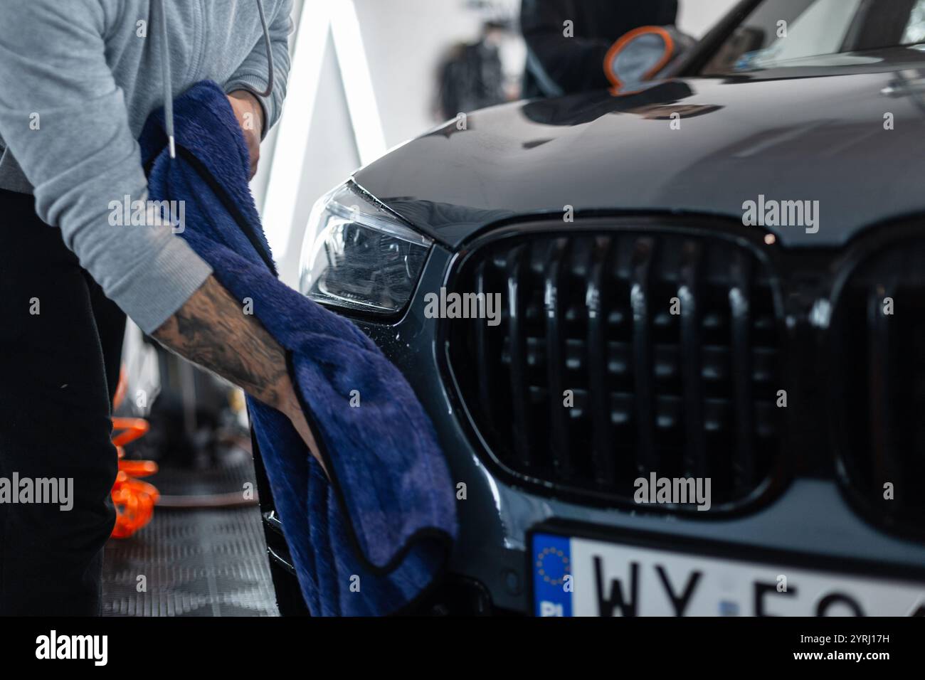 Professional car wash man wipes a car dry with a microfiber cloth in a ...