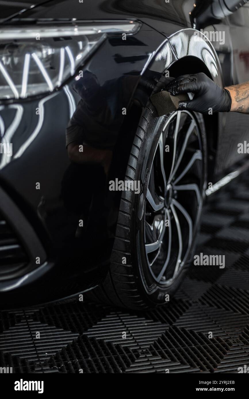 Professional man washing car and wheels in garage. Detailing. Tire care ...