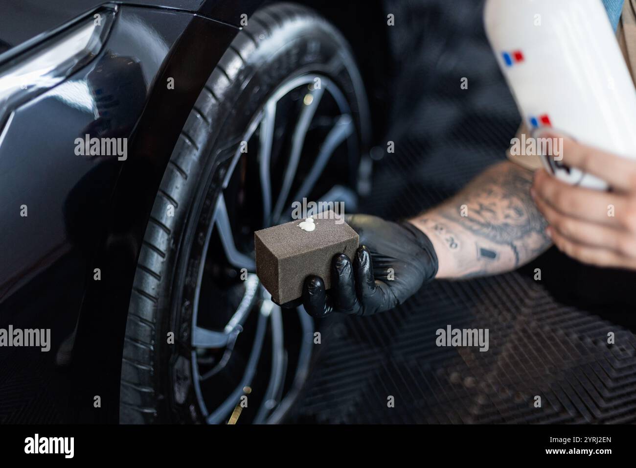 Professional man washing car and wheels in garage. Detailing. Tire care ...