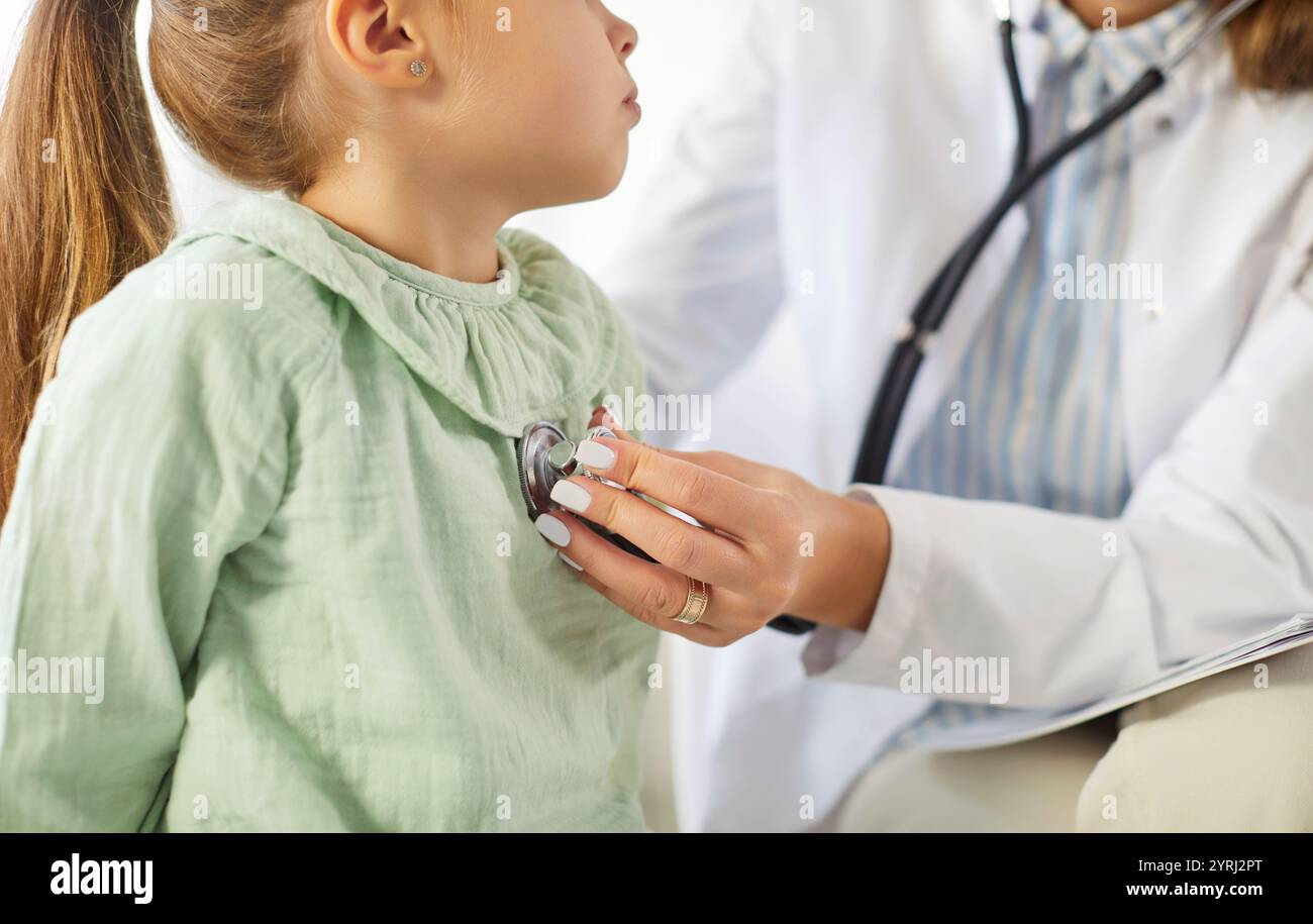 Closeup of female doctor examining child with stethoscope sitting in ...