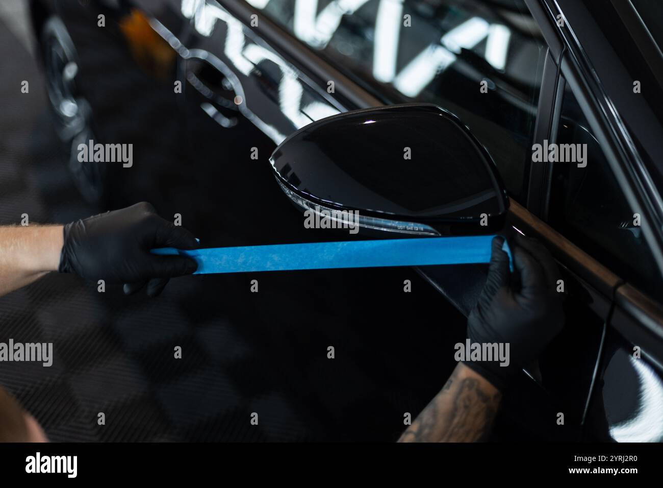 professional man tapes a car with masking tape before polishing ...