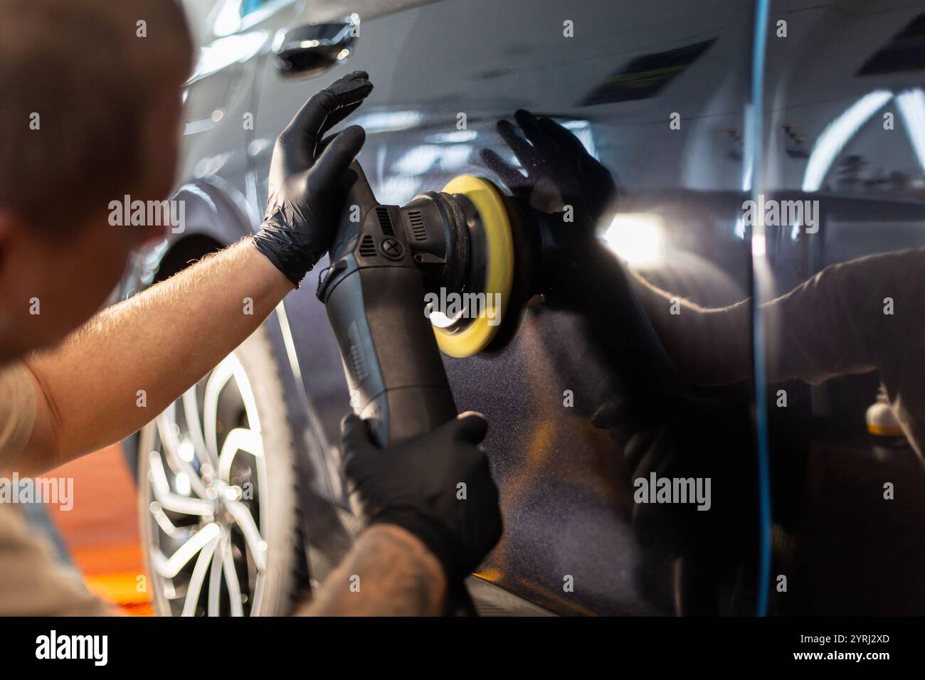 Professional man polishing black car and removing scratches in ...