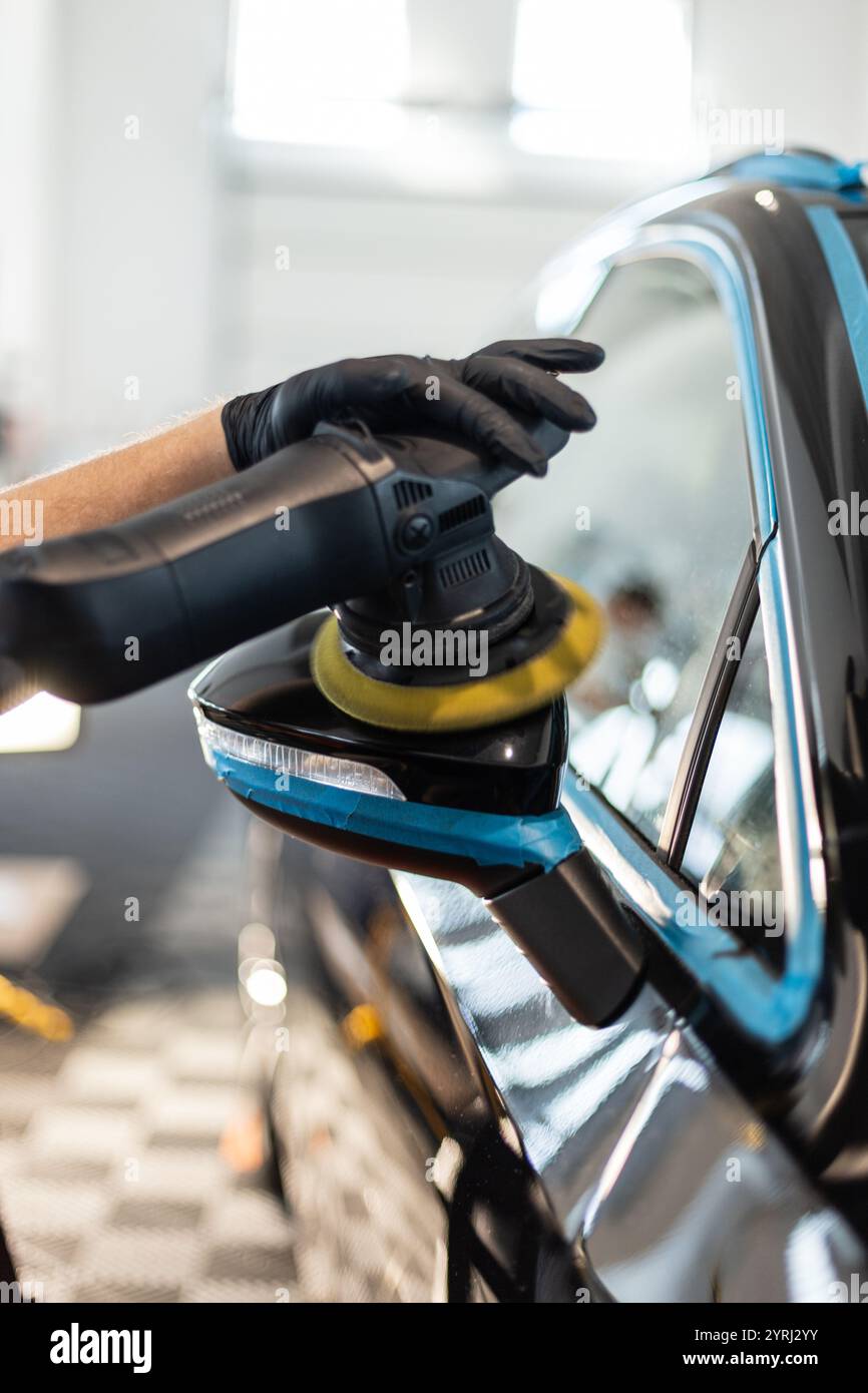 Professional man polishing black car and removing scratches in ...