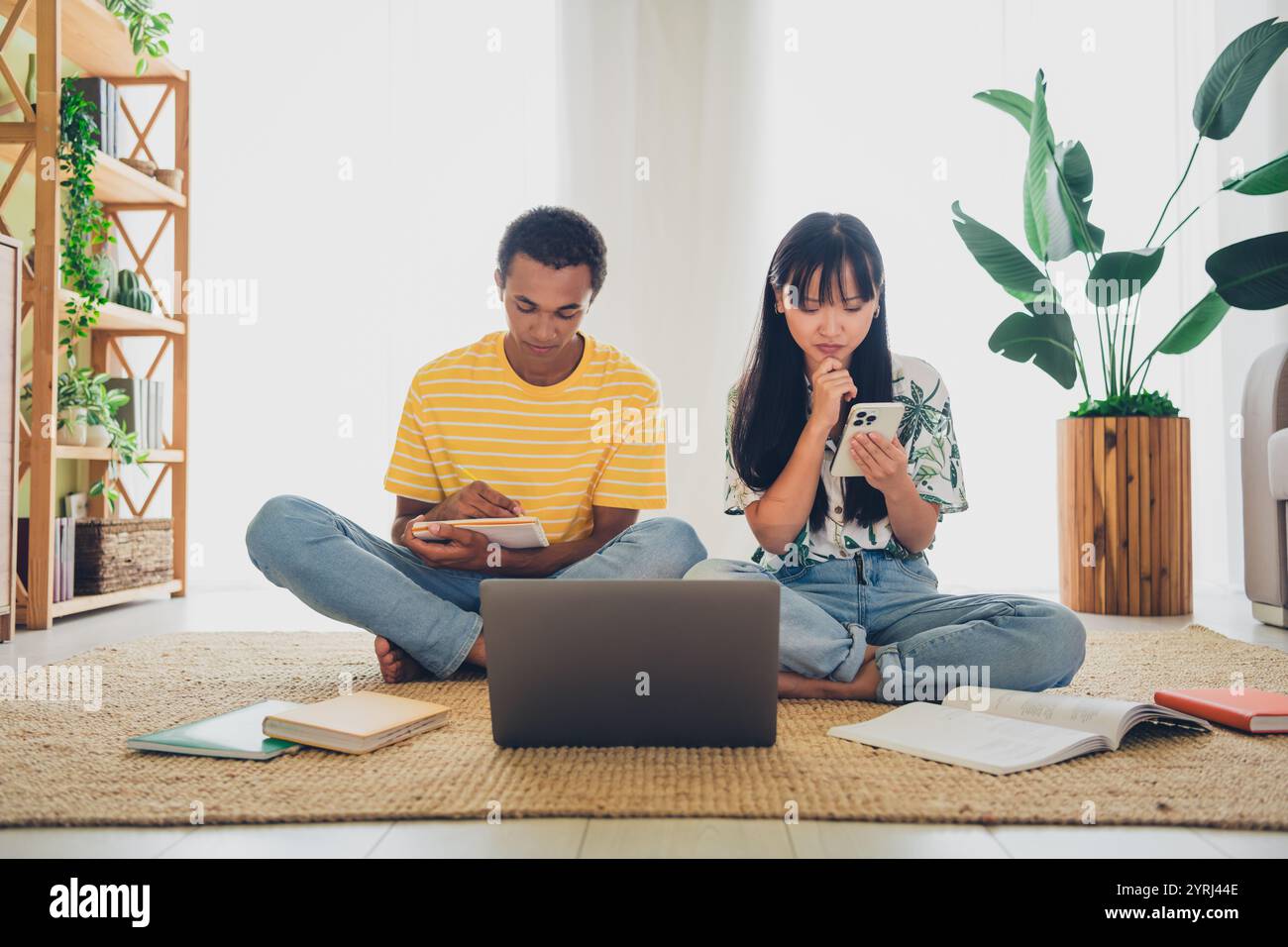 Photo of thoughtful clever cute multiethnic couple sitting floor doing ...