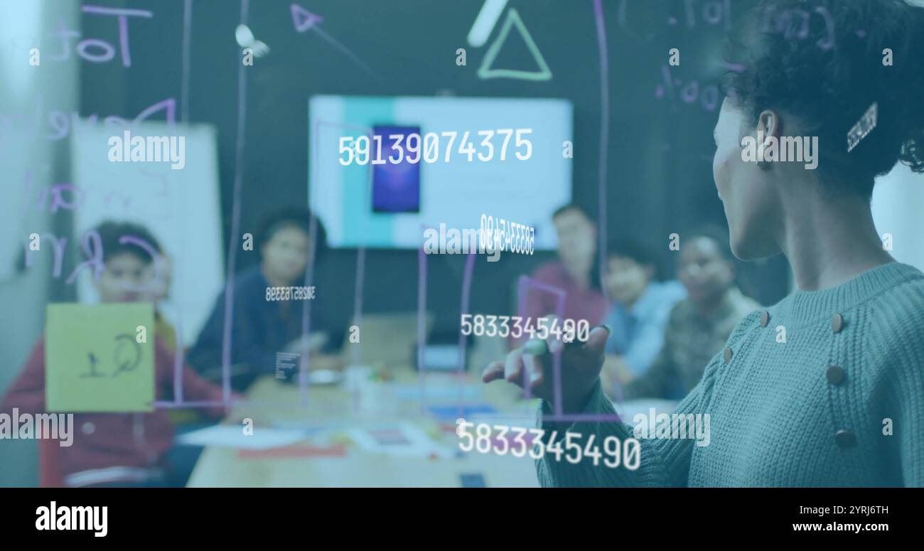 Writing numbers on transparent board, woman with colleagues in ...