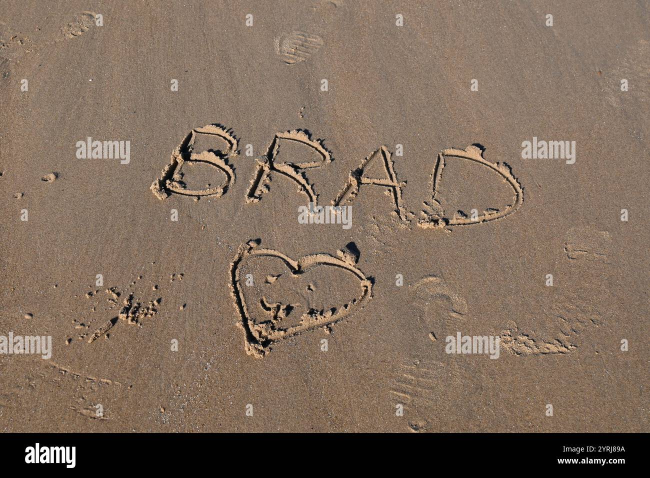 The name Brad is drawn into the sand with a heart below it Stock Photo ...