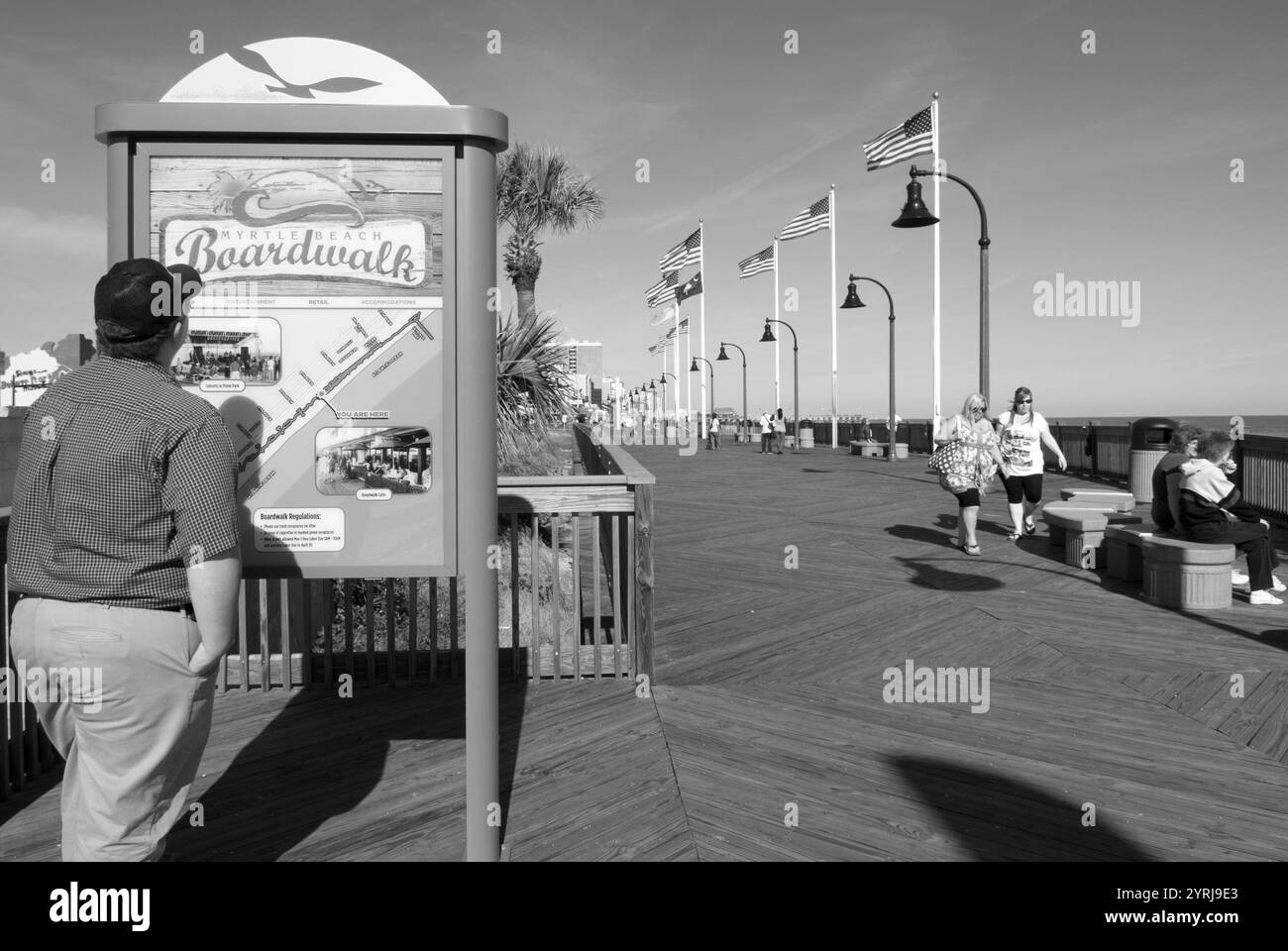 Male Caucasian tourist reading a directional sign on a wooden boardwalk ...
