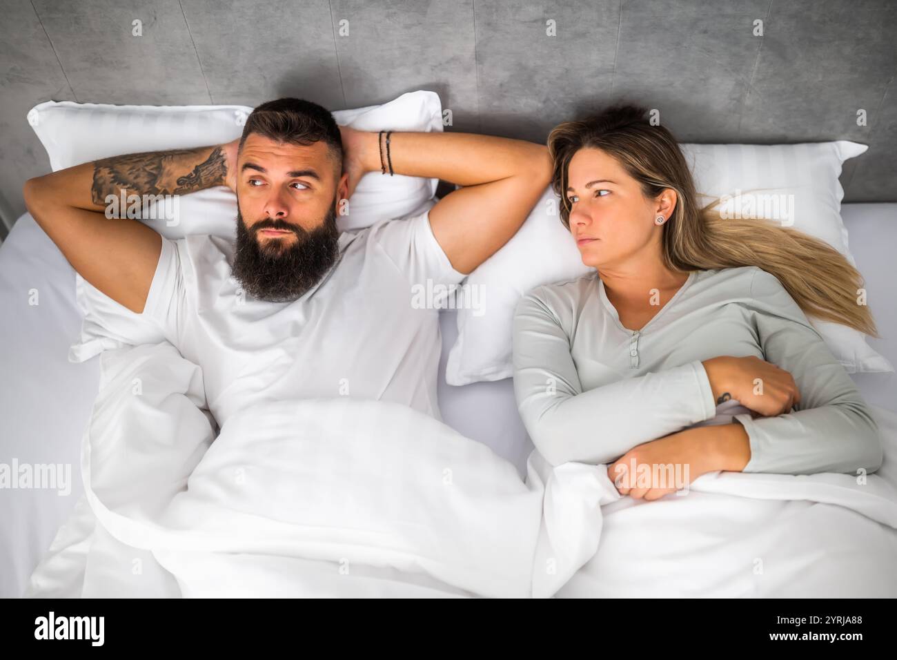 Couple is lying in bed. They are angry and not talking to each other ...