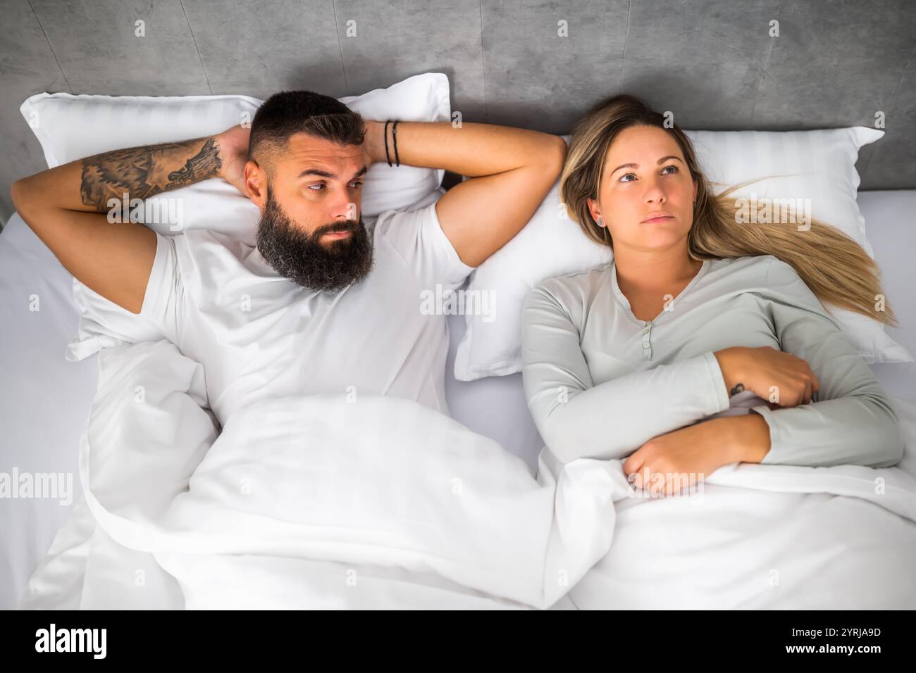 Couple is lying in bed. They are angry and not talking to each other ...