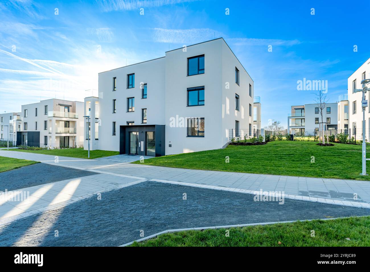 Modern residential complex with green areas and pathways on sunny day ...