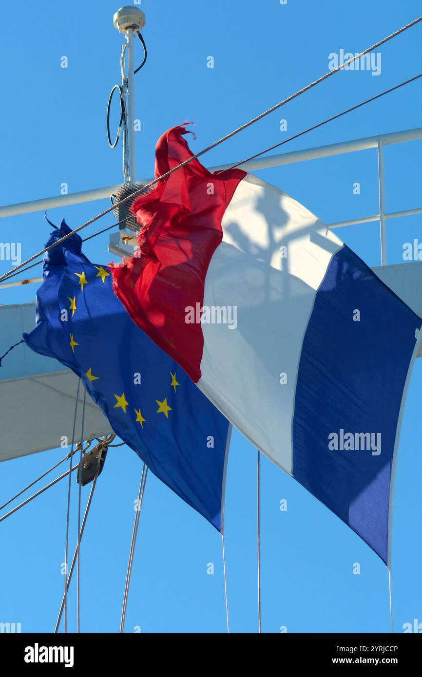 The European Union and French flags waving on a ship's mast against a ...