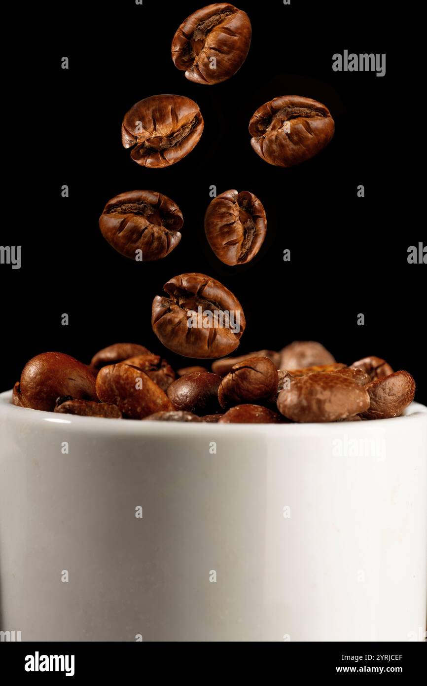 Macro photograph showing coffee beans falling on a white coffee cup ...