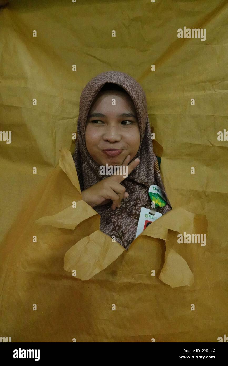 A woman wearing a hijab takes a photo with a torn paper background ...
