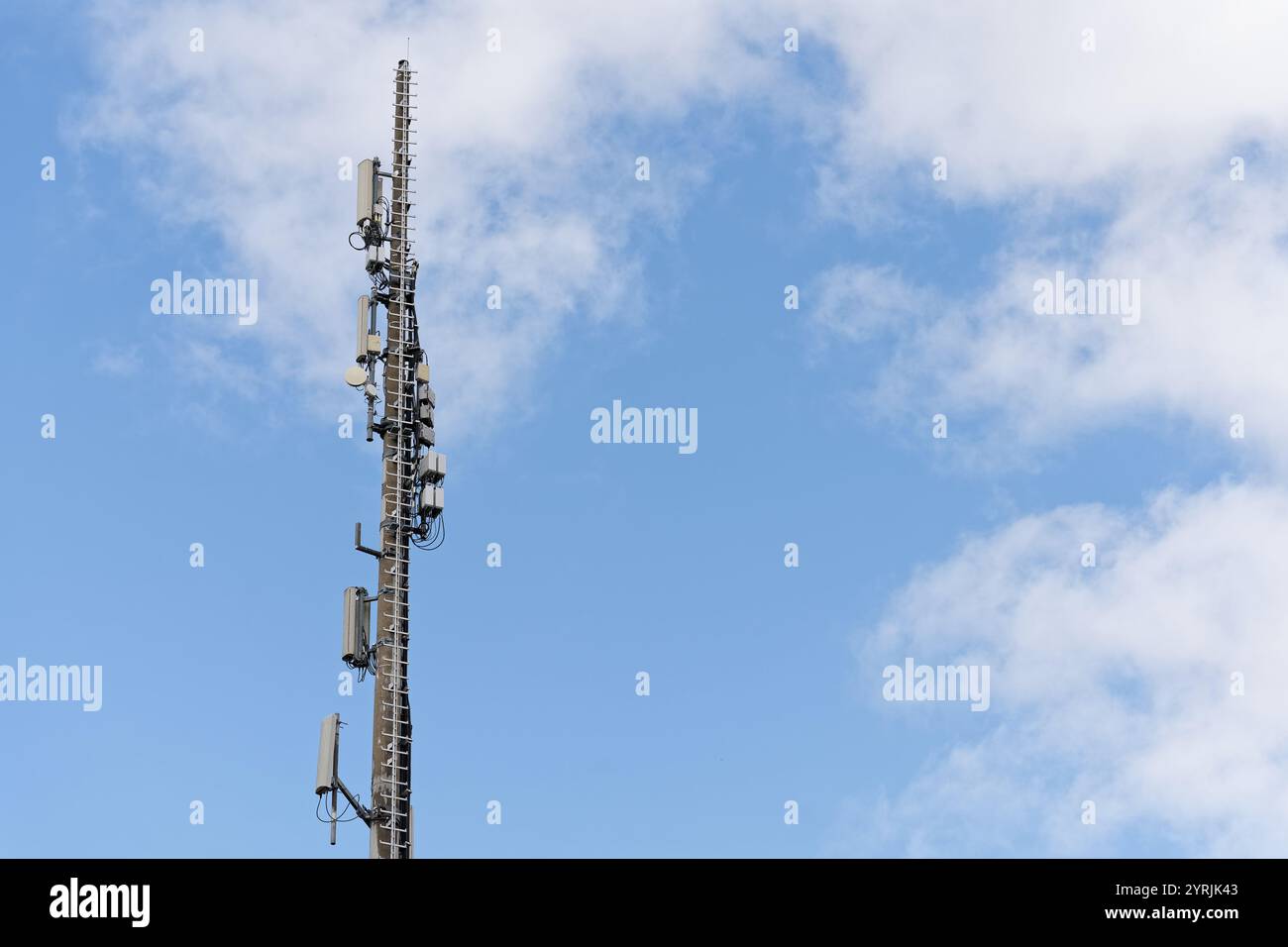 Telecommunication antenna tower with transmitters against blue sky with ...