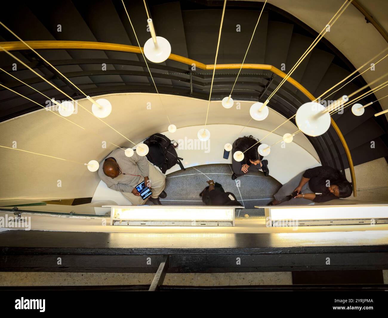 People sitting waiting & winding staircase from above with modern ...