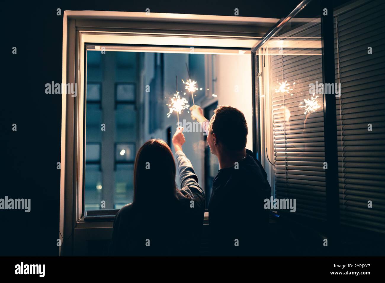 New Year's window sparkler firework. Couple celebrating at home. Eve ...