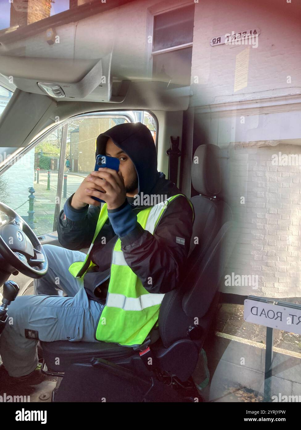 A van driver films video from his driving position on his mobile ...