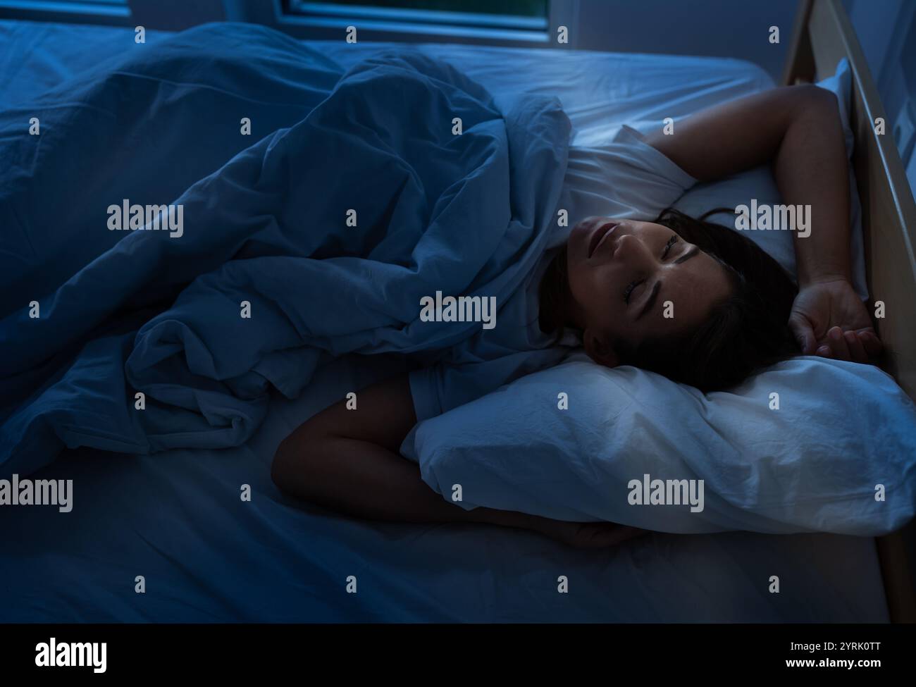 Pretty young woman sleeping restful in bed at morning with sun ray ...