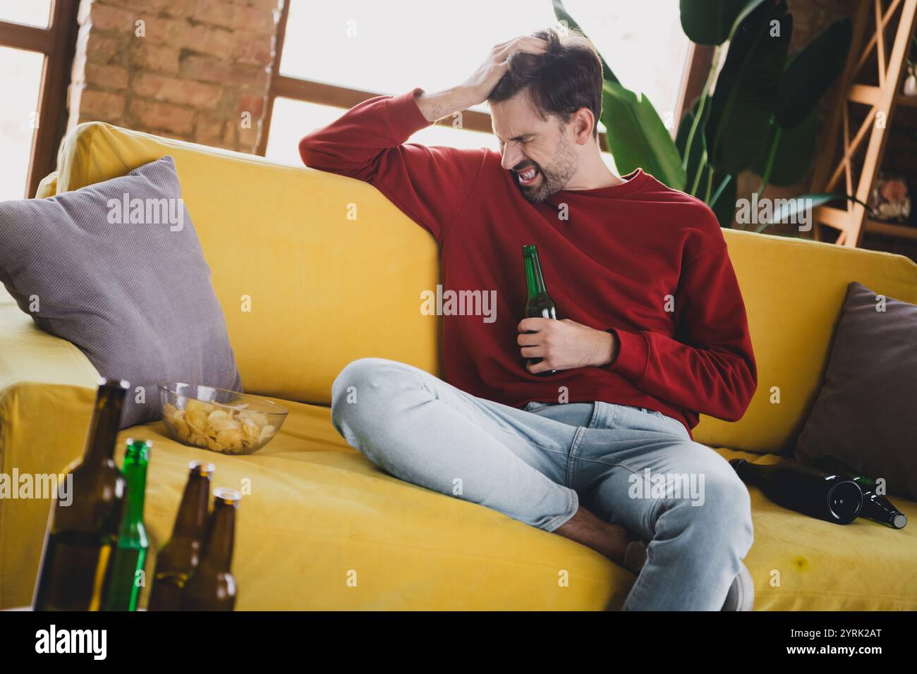 Young man enjoying a laid-back weekend at home with beer and snacks in ...
