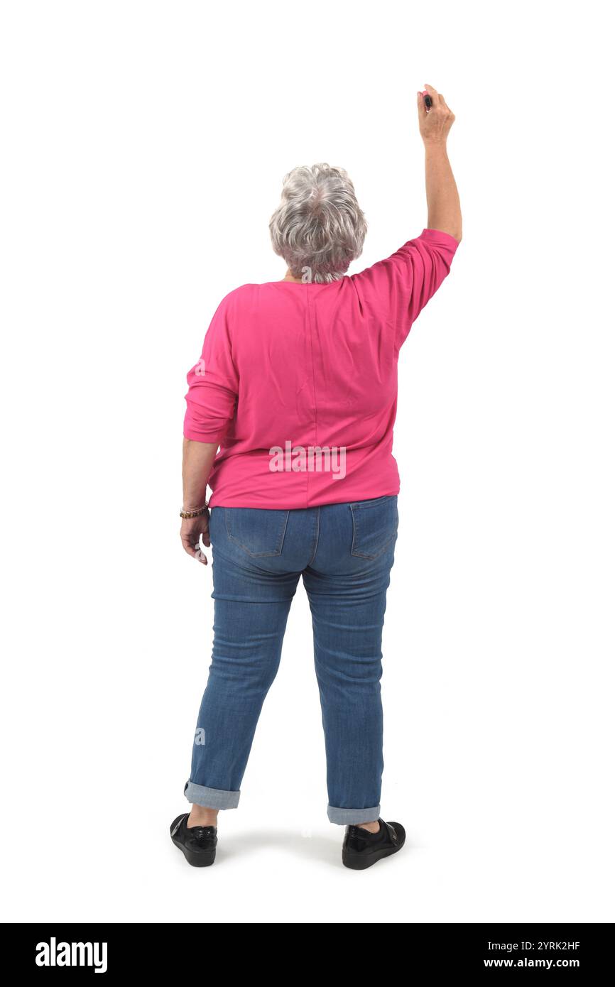 back view of senior woman drawing with marker with raised arm on white ...