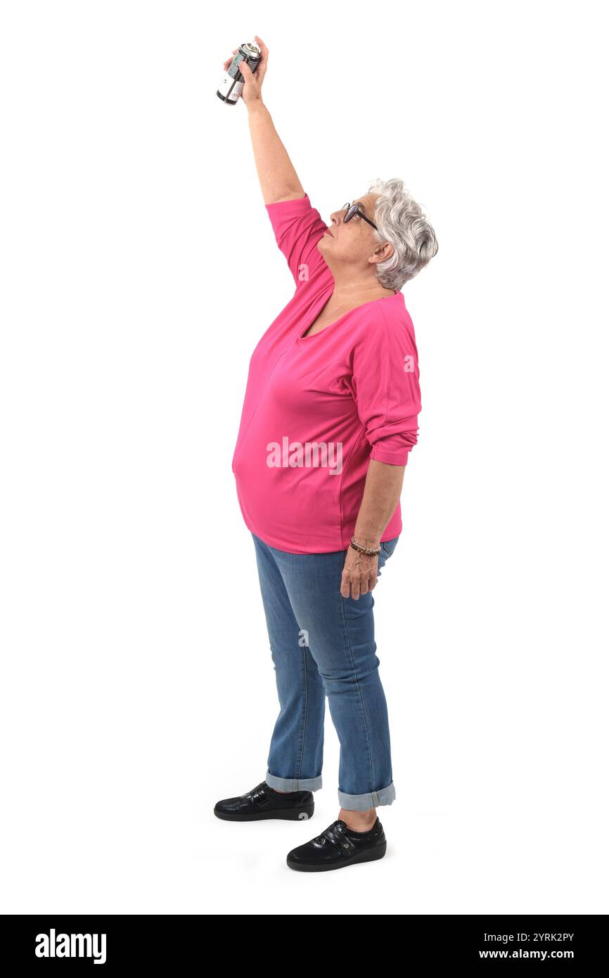 side view of a senior woman spray painting with arms raised on white ...