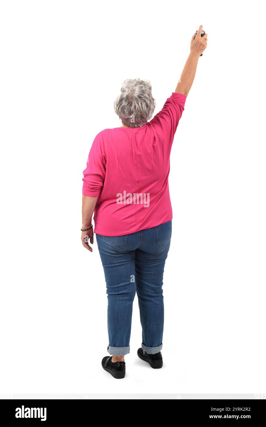 back view of a senior woman spray painting with arms raised on white ...